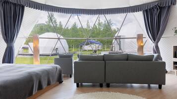 Acomodação em tenda moderna com sofá, uma cama, um tapete branco e fofo, e vista para o exterior.