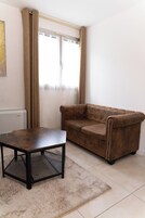 Uma sala de estar com um sofá de couro marrom, uma mesa de centro de madeira e um tapete bege.