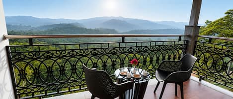 Uma varanda com mesa e cadeiras, com vista para uma paisagem montanhosa.