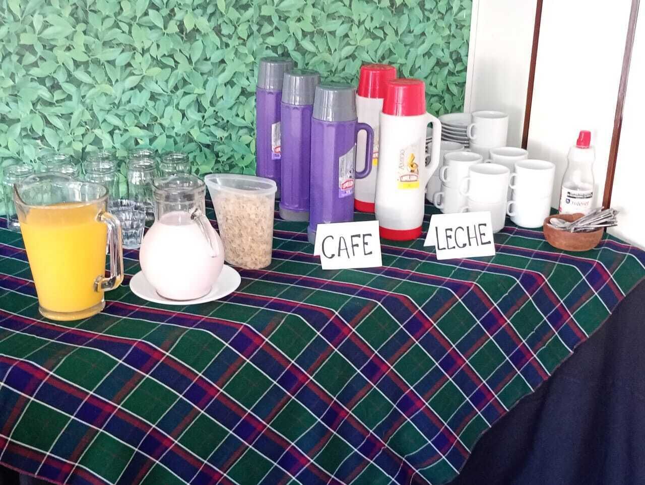 Disposição para o café da manhã com itens identificados para café e leite, incluindo um jarro de suco de laranja, um bule e diversos recipientes.
