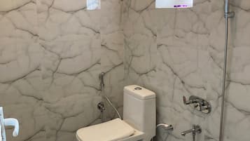 Um banheiro com vaso sanitário, chuveiro e uma pequena janela.