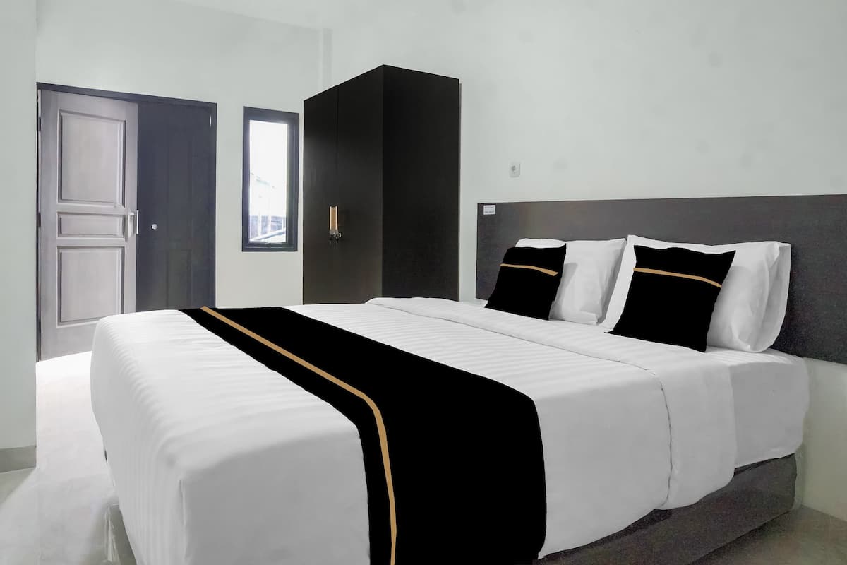 Quarto de hotel com cama, guarda-roupa, porta e janela.