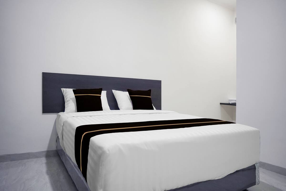 Um quarto moderno com uma cama, um criado-mudo e uma prateleira na parede.