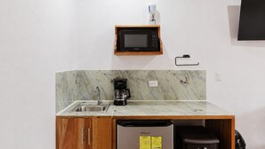 Uma cozinha compacta equipada com micro-ondas, cafeteira, pia e lava-louças.
