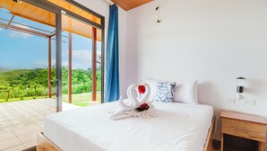 Um quarto com cama, mesa de cabeceira e vista para um jardim.
