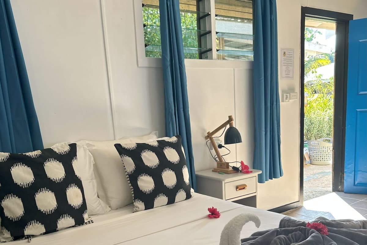 Quarto de hotel com cama, mesa de cabeceira, luminária e vista para o exterior.