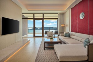 Uma sala de estar moderna com televisão de tela plana, um sofá, uma mesa de centro e vista para o mar.