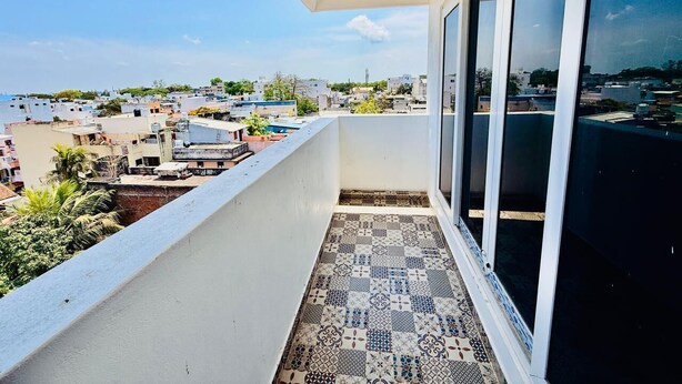 Varanda com piso estampado, janelas amplas e vista para uma área residencial.