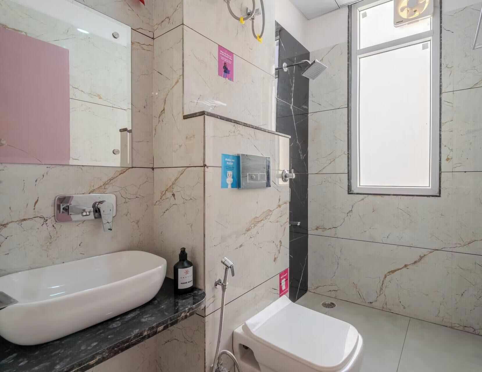Casa de banho com lavatório branco, chuveiro manual, sanita e cabine de duche.