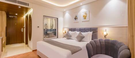 Quarto de hotel moderno com uma cama grande, área de estar e vista para a cidade.