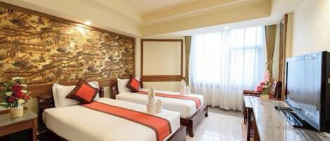 Quarto de hotel com duas camas, uma televisão e um painel decorativo.