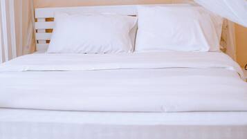 Cama bem arrumada com roupa de cama branca e dossel.