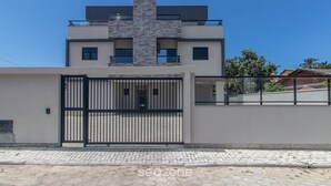 Um edifício moderno de dois andares, com entrada fechada por portão, teto plano e um caminho de tijolos que leva ao portão.