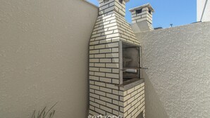Forno de tijolos construído ao ar livre, anexado a uma parede da casa.