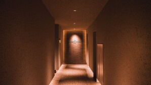 Um corredor com parede de tijolos e uma placa com a inscrição 'ISUBAKIMORI'.