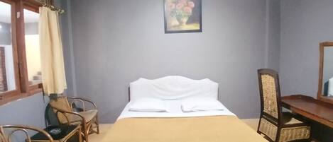 Quarto com cama, cadeira, escrivaninha e um quadro na parede.