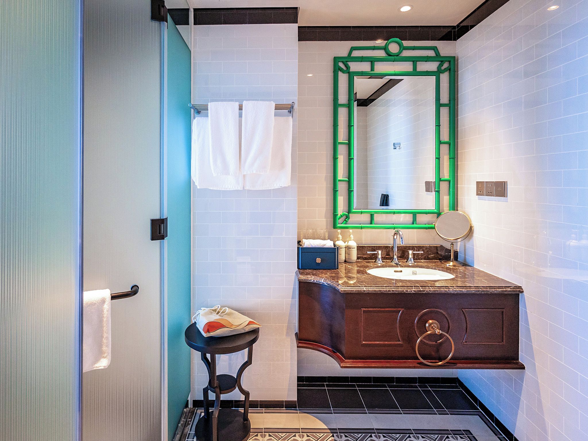 Casa de banho moderna com lavatório de mármore, espelho com moldura verde e porta-toalhas.