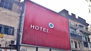 Uma placa vermelha com a palavra 'HOTEL' e um logotipo, indicando um estabelecimento hoteleiro.