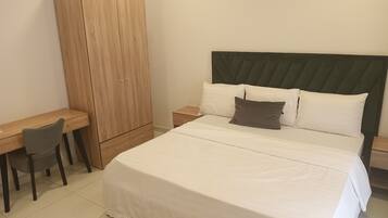 Um quarto com cama, escrivaninha e guarda-roupa.