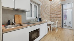 Uma cozinha moderna com armários brancos, um exaustor Bosch, uma janela, uma parede de tijolos e uma área de jantar com mesa e cadeiras.