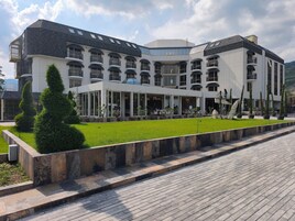 Um hotel de vários andares com design arquitetônico moderno, com varandas, grandes janelas e um gramado bem cuidado.