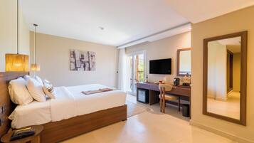 Quarto de hotel moderno com cama, escrivaninha, cadeira, televisão e um espelho grande.