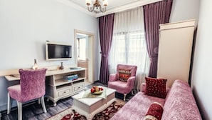 Uma sala de estar com sofá, poltrona e escrivaninha com televisão.