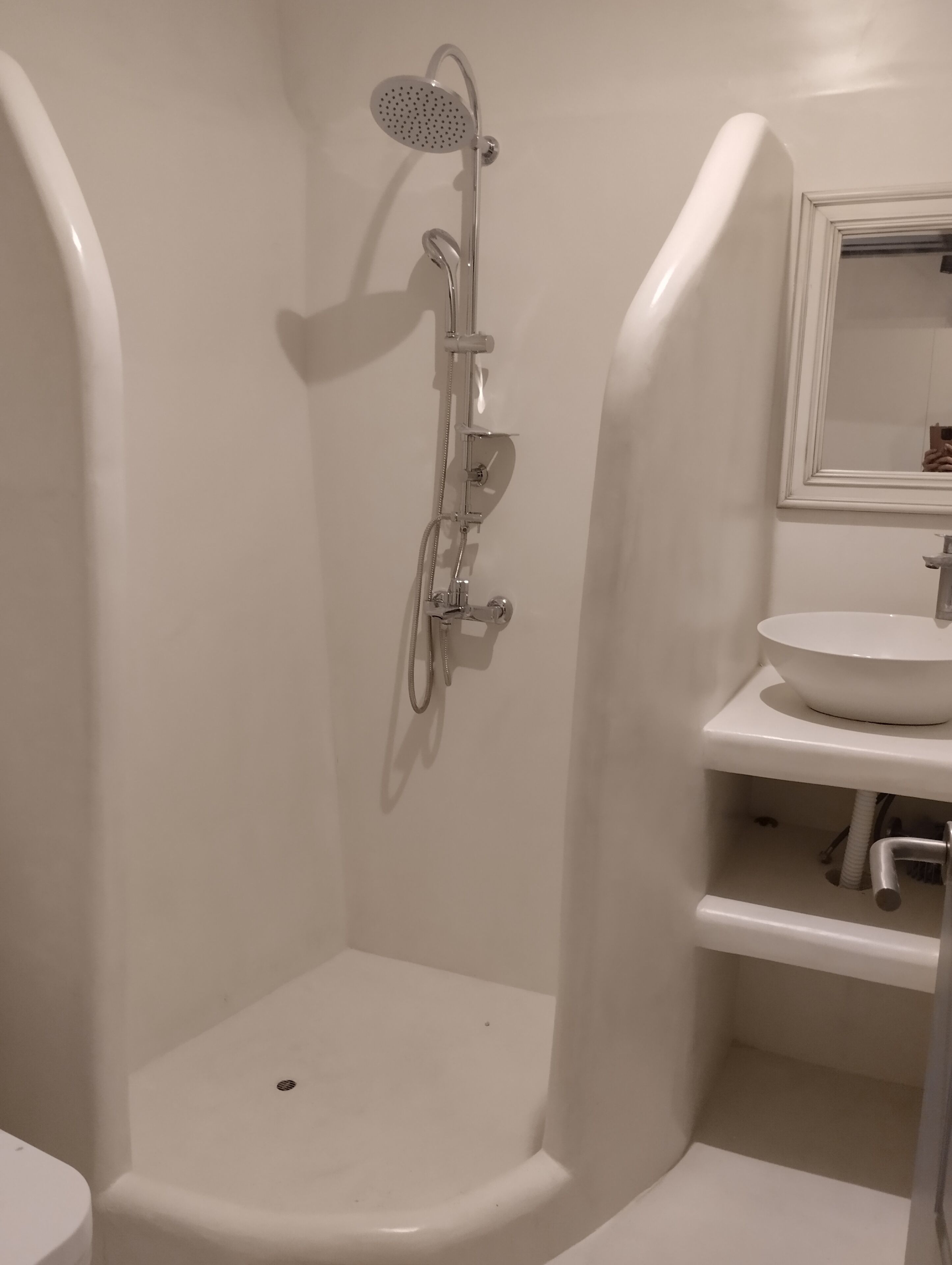 Uma casa de banho com chuveiro, lavatório e espelho.