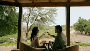 Uma área de estar coberta ao ar livre com vista para vinhedos e árvores.