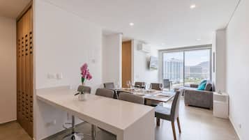 Área de refeições moderna com uma mesa comprida, cadeiras e vista para a cidade através de grandes janelas.