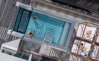 Piscina no terraço com trampolim, cadeira de salva-vidas e área de estar com espreguiçadeiras.