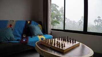 Um tabuleiro de xadrez sobre uma mesa redonda em um quarto com um sofá e uma janela.