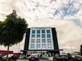 Um edifício de hotel moderno com fachada plana, diversas janelas e uma placa com a inscrição 'HOTEL PREMIUM'.