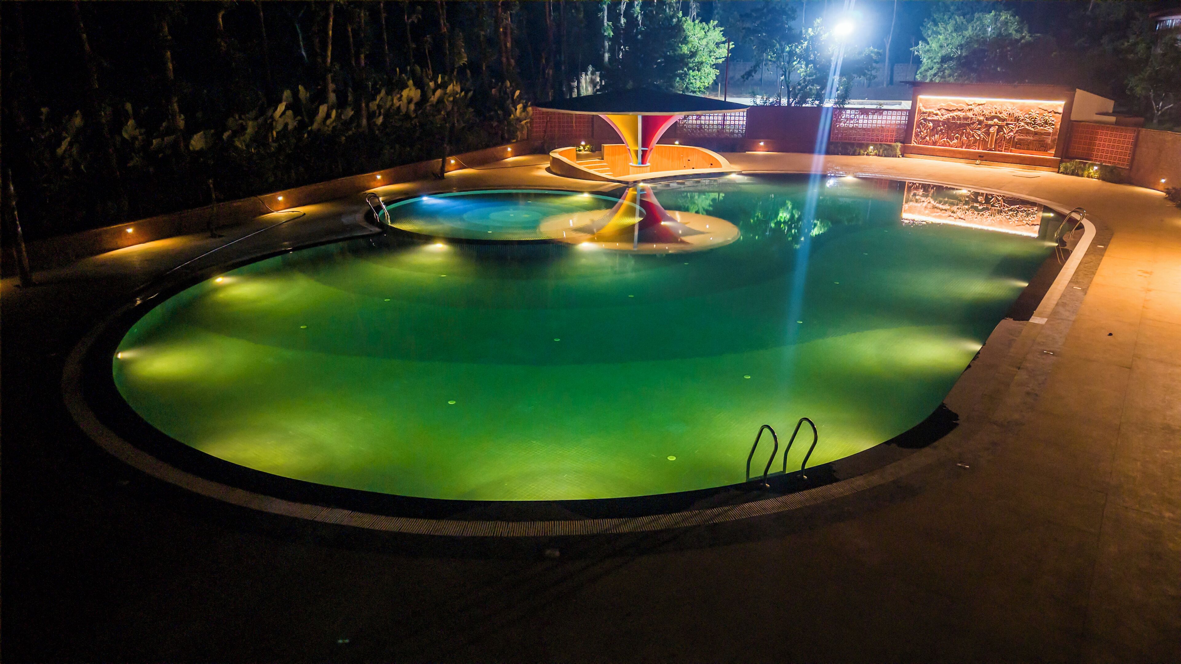 Piscina com design circular, rodeada por um muro de pedra e um deck de madeira.