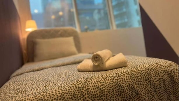 Quarto de hotel com uma cama, janela e luminária.