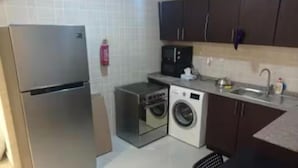 Cozinha compacta com geladeira, micro-ondas, máquina de lavar e pia.
