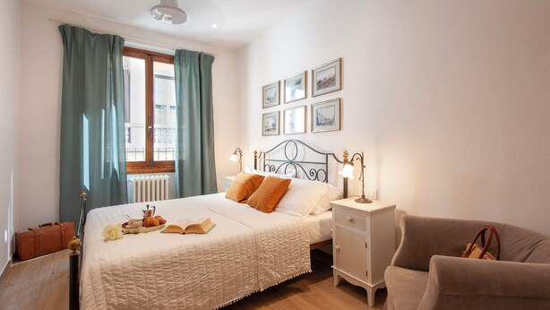 Quarto bem arrumado com cama, mesa de cabeceira e uma cadeira.