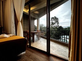 Quarto com cama, mesa, cadeira e varanda com vista para o exterior.
