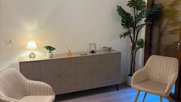 Uma sala de estar moderna com duas cadeiras, um aparador, um abajur e um vaso com planta.