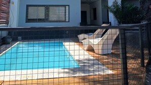 Um edifício de dois andares chamado "Carlos Paz Lodge" com uma piscina em frente.