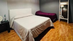Quarto com cama, mesa de cabeceira, cômoda e espelho.