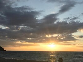 Um pôr do sol sobre o oceano com nuvens no céu.