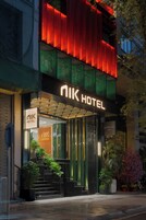 Exterior do Hotel Nik com fachada moderna, grandes janelas de vidro e uma entrada destacada com degraus que levam à porta.