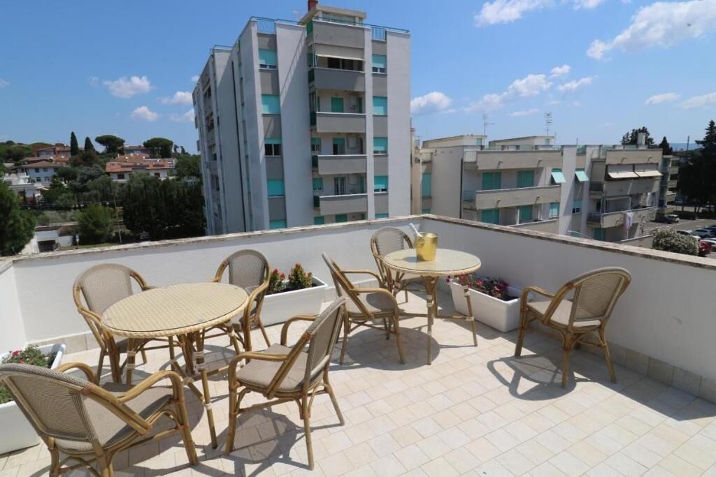 Terraço no terraço com móveis de vime e uma pequena mesa, com vista para uma área residencial com edifícios altos.