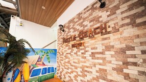 Uma área de recepção com teto de madeira, um mural representando uma cena de praia e uma placa com a inscrição "Turtle Beach Resort".