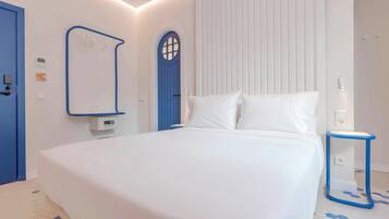 Quarto de hotel com uma cama, uma porta azul, uma parede branca e uma mesa de cabeceira.
