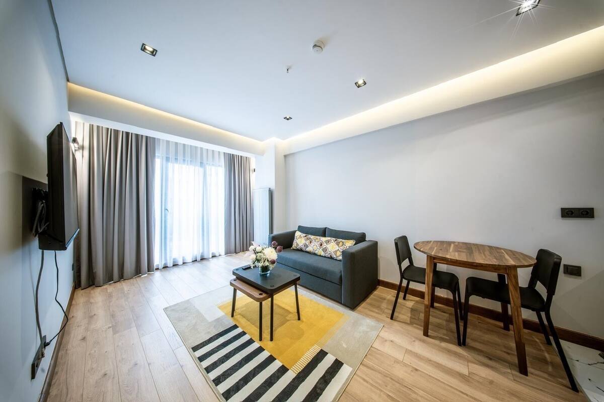 Uma sala de estar moderna com sofá, mesa de centro e mesa de jantar.