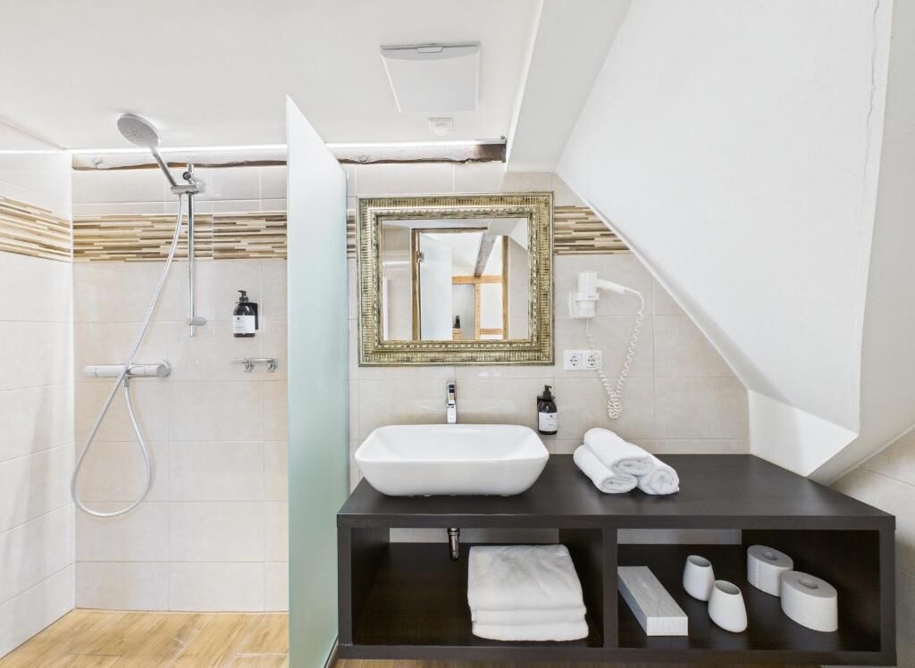 Uma casa de banho moderna com chuveiro, pia e toucador com toalhas e artigos de higiene pessoal.
