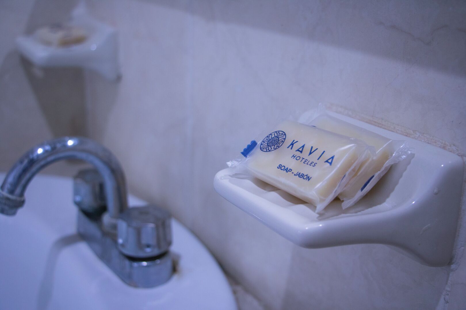 Uma pia de banheiro com um dosador de sabão com a etiqueta 'KAVIA HOTELES SOAP-JABÓN'.