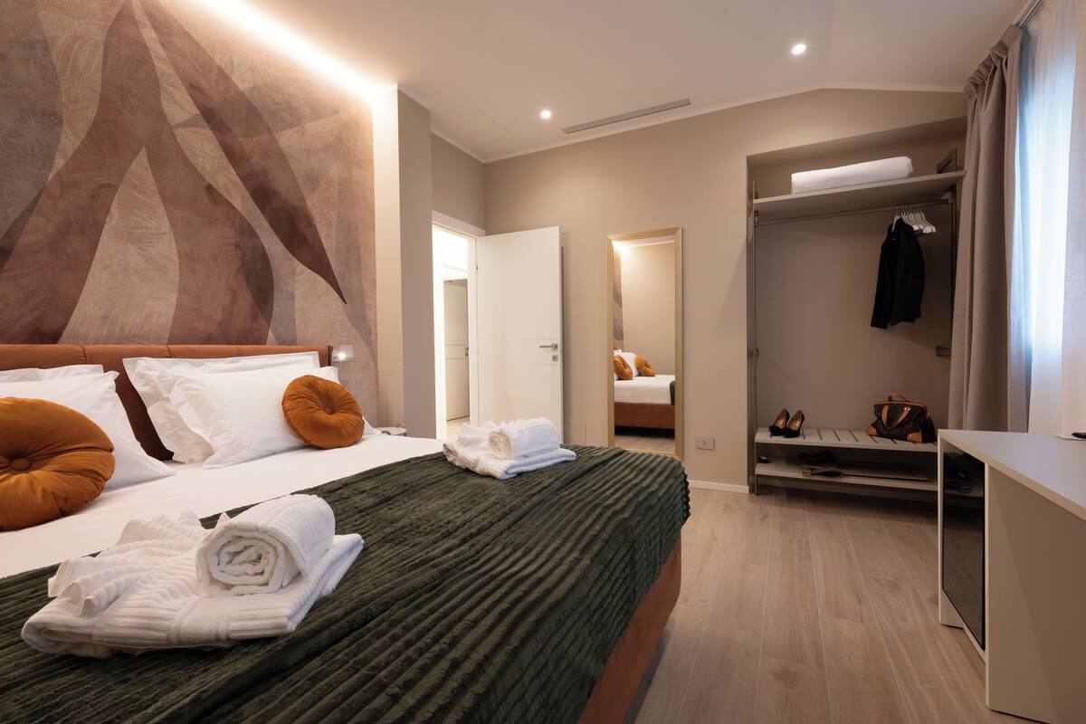 Quarto de hotel moderno com uma cama grande, um closet espaçoso e um espelho.